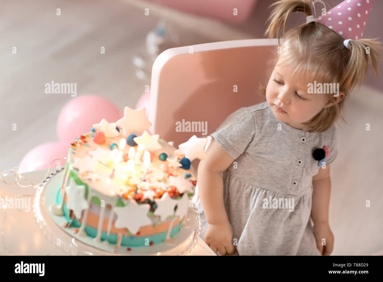 Cute little girl with birthday cake sitting on chair in room Stock ...