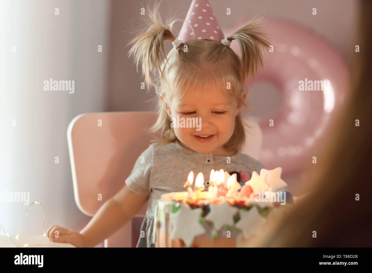 Cute little girl with birthday cake sitting on chair in room Stock ...