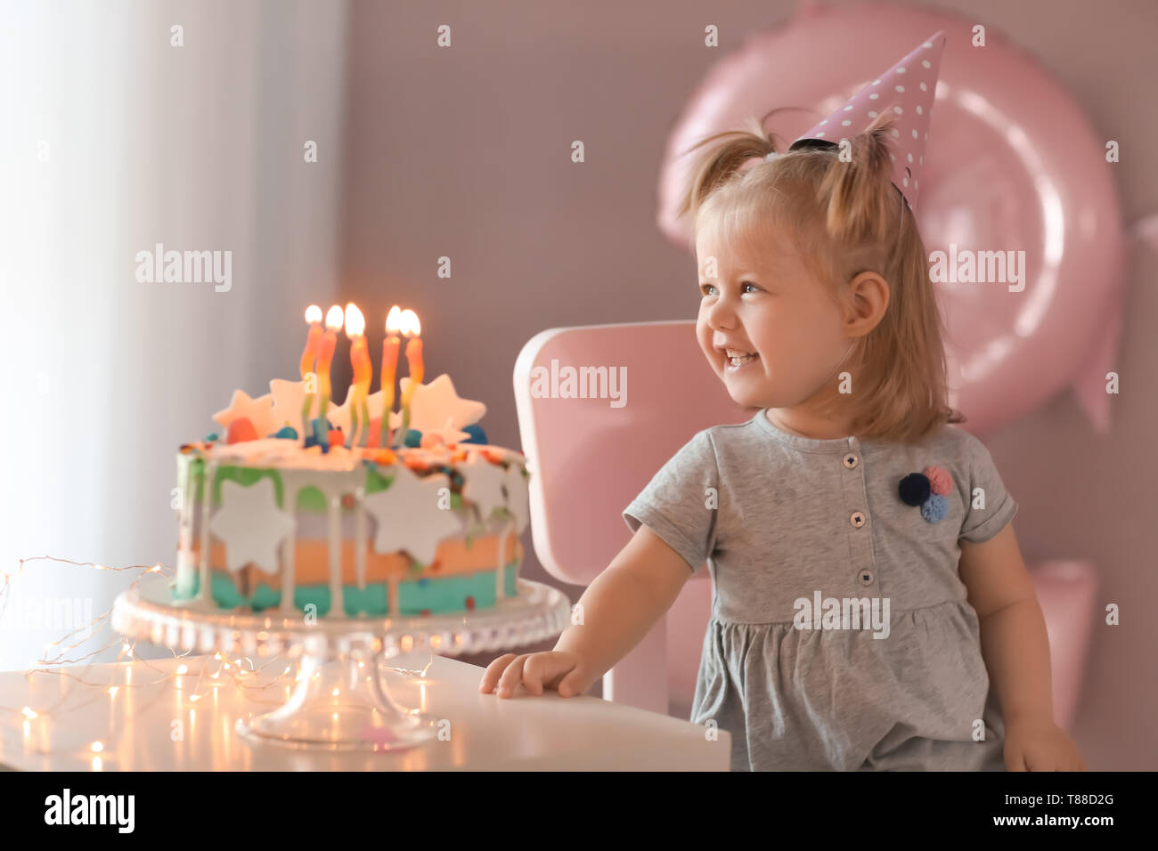 Cute little girl with birthday cake sitting on chair in room Stock ...