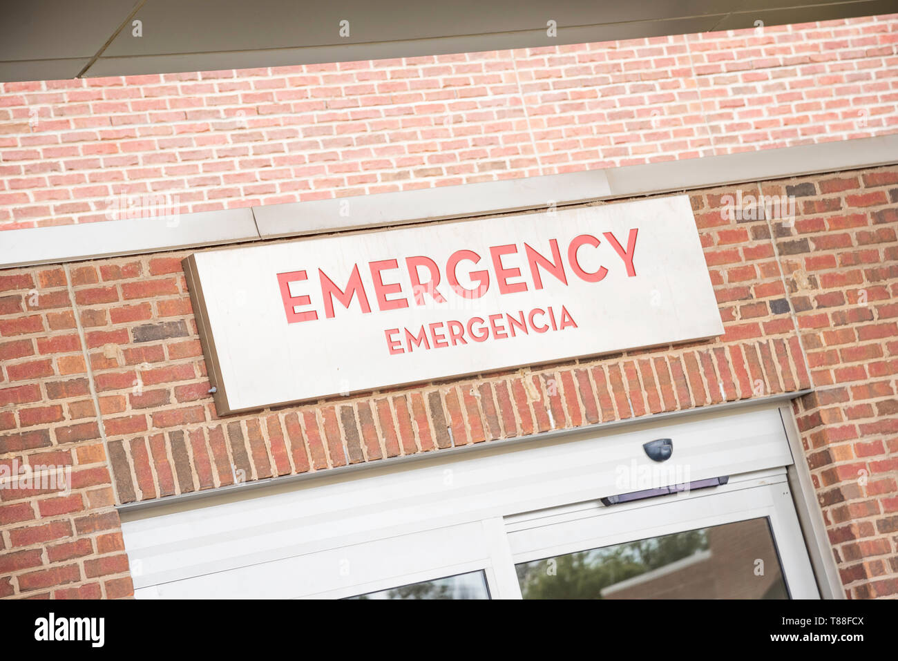 A red emergency directional sign and marker in English with Spanish ...