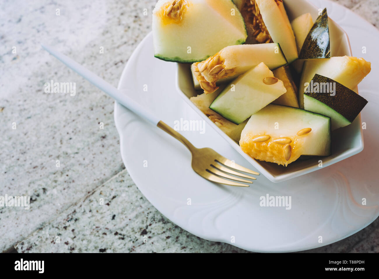 Melon toad skin cut in geometric bowl, on granite countertop, Colorful ...