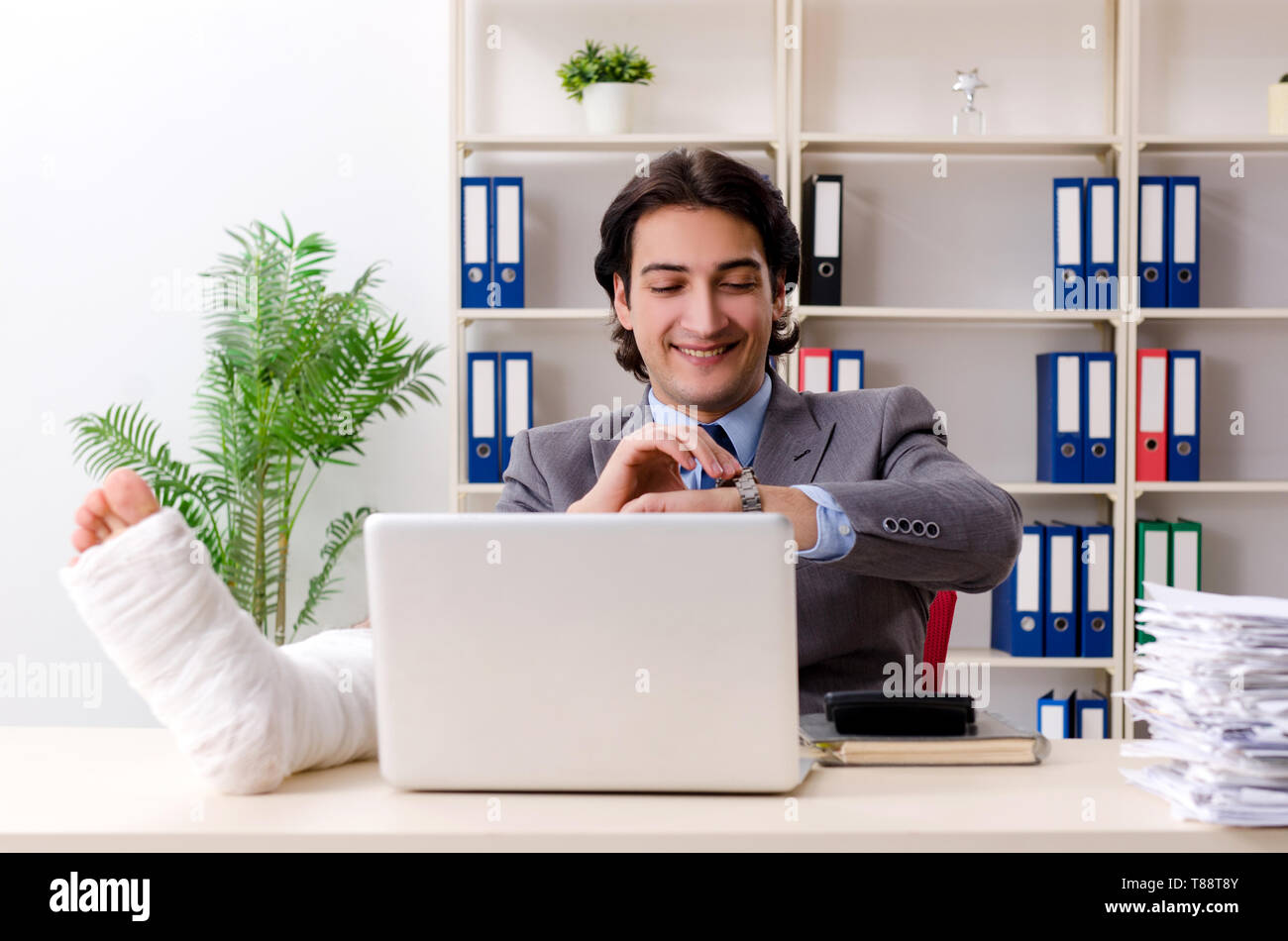 Leg injured employee working in the office Stock Photo - Alamy