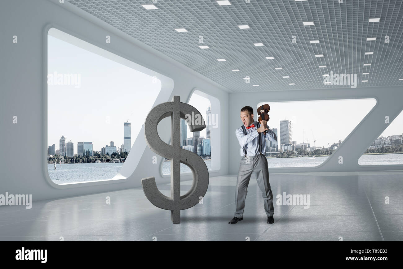 Determined banker man in modern office interior breaking dollar figure ...