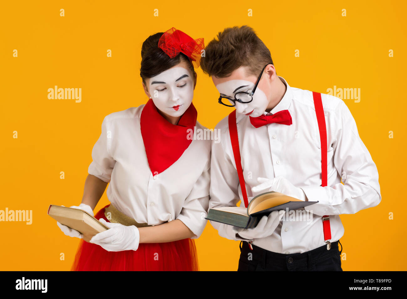 portrait of mime couple artist reading book isolated on yellow ...