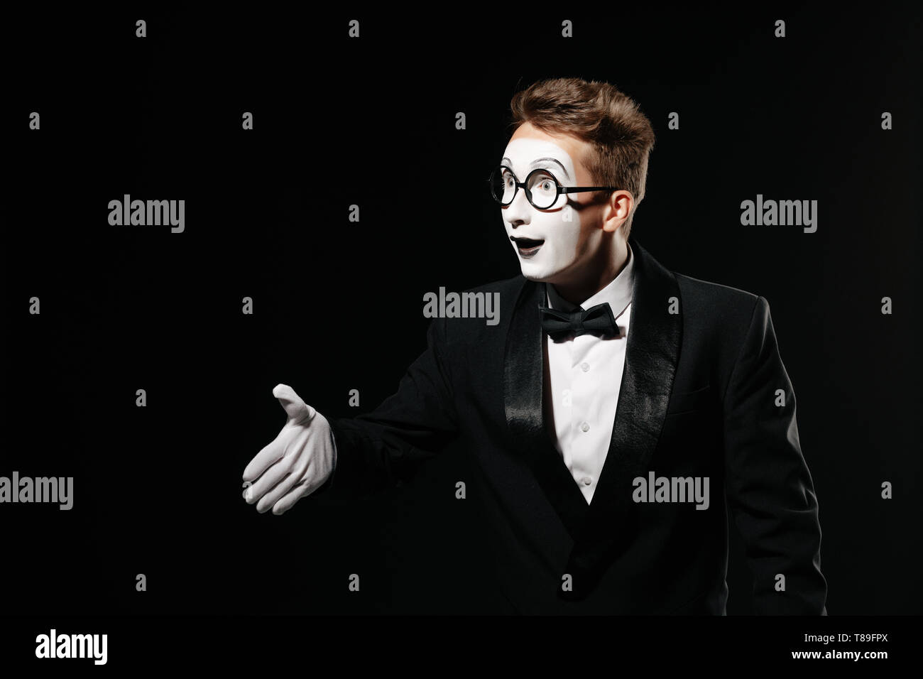 portrait of mime man in tuxedo and glasses giving hand for handshake on ...