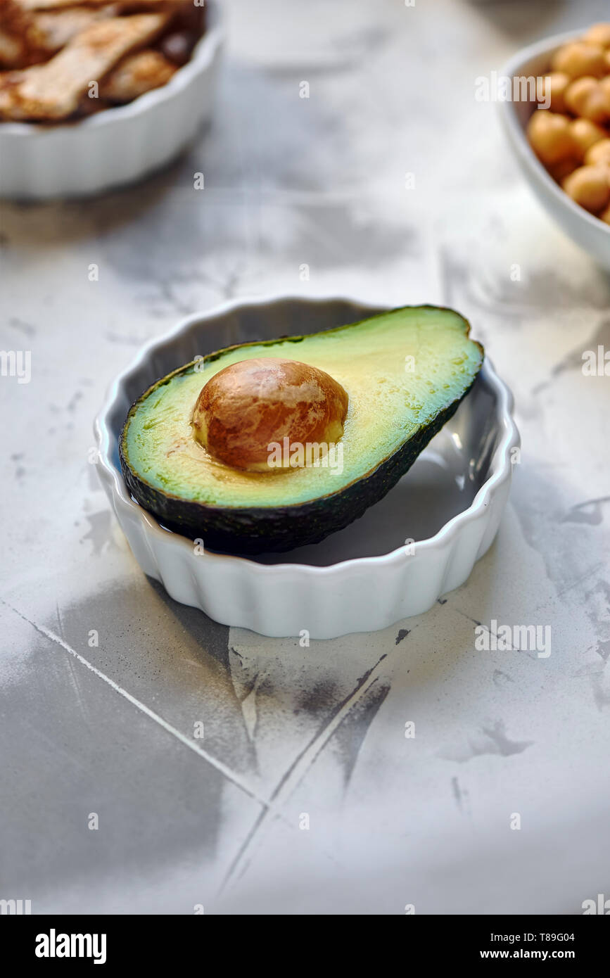 Avocado split in half, surrounded by ingredients to prepare a cold dish ...
