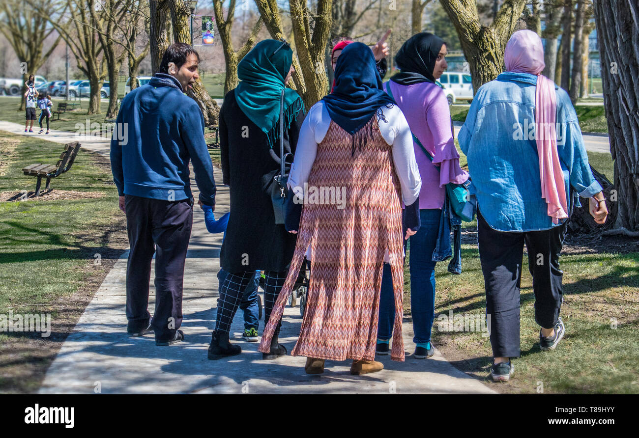 Some young Muslim adults, traditionally dressed, walking thru the park ...