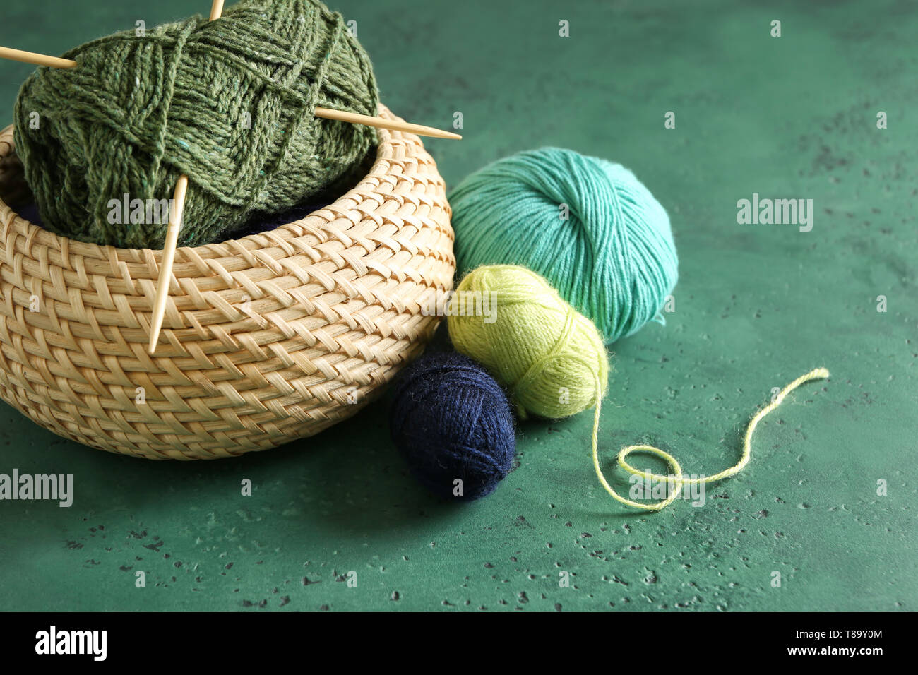 Wicker bowl with knitting yarn on table Stock Photo - Alamy