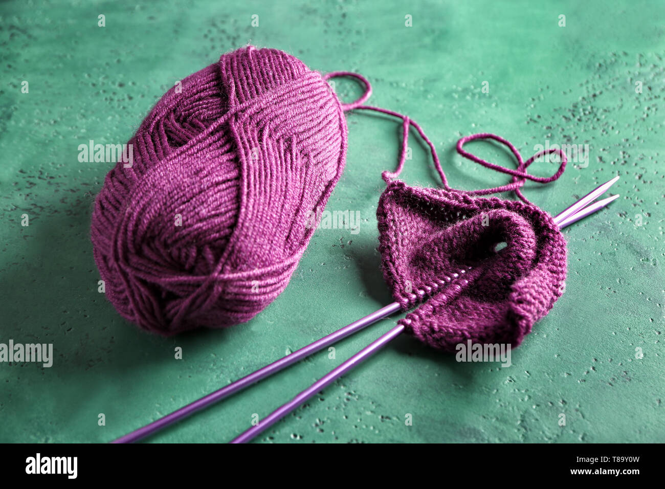 Knitting yarn with unfinished clothes on color textured background ...