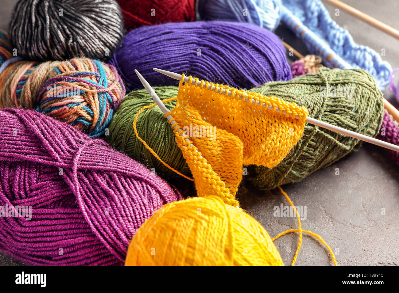 Knitting yarn, needles and unfinished clothes on grey textured ...