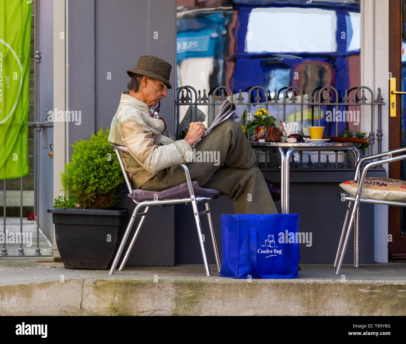 Man sat outside a café reading the newspaper and drinking coffee Stock ...