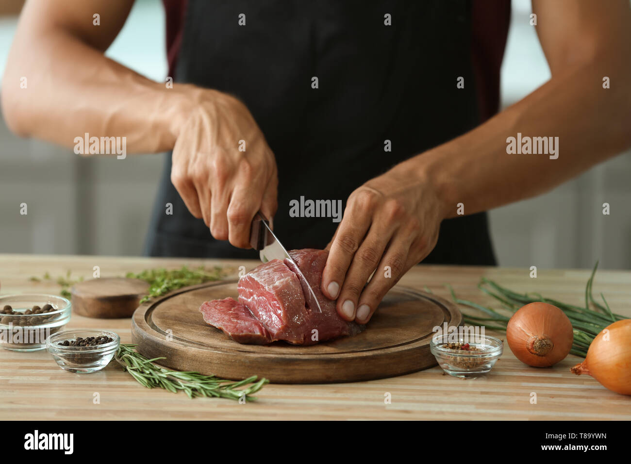 Man cutting raw meat on board in kitchen Stock Photo - Alamy