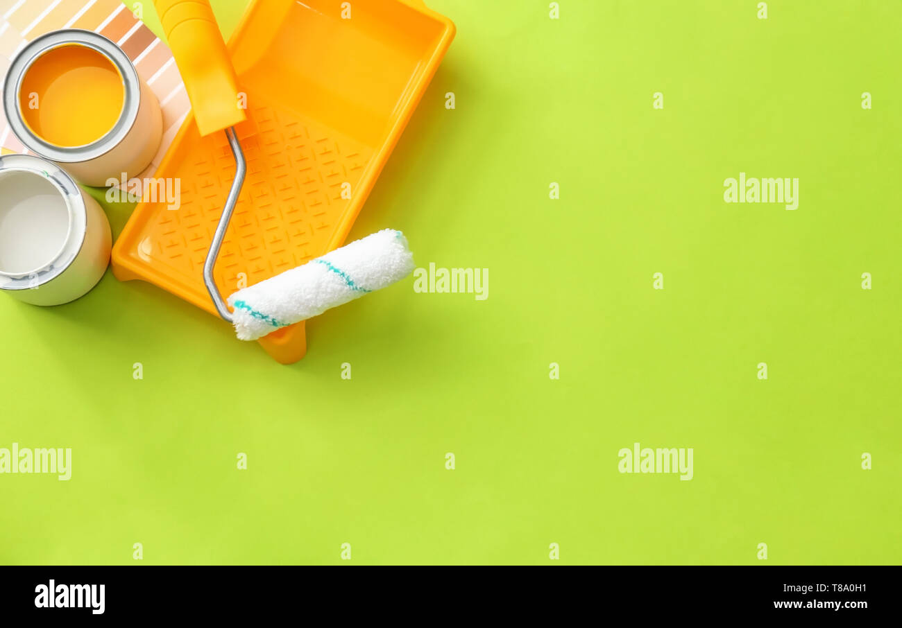 Paint cans and tray with roller on color background Stock Photo - Alamy