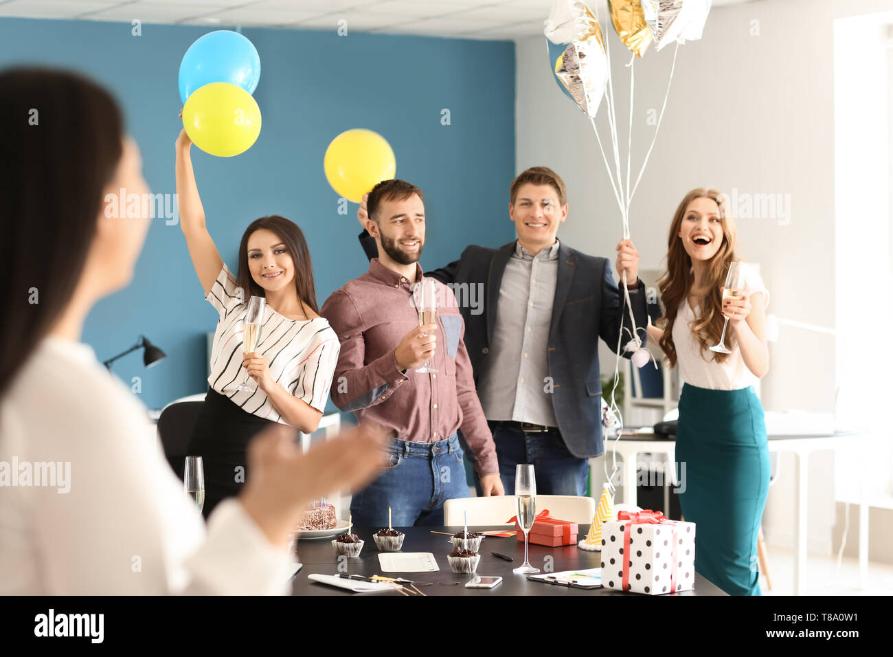 Happy colleagues at surprise party for young woman on her birthday in ...