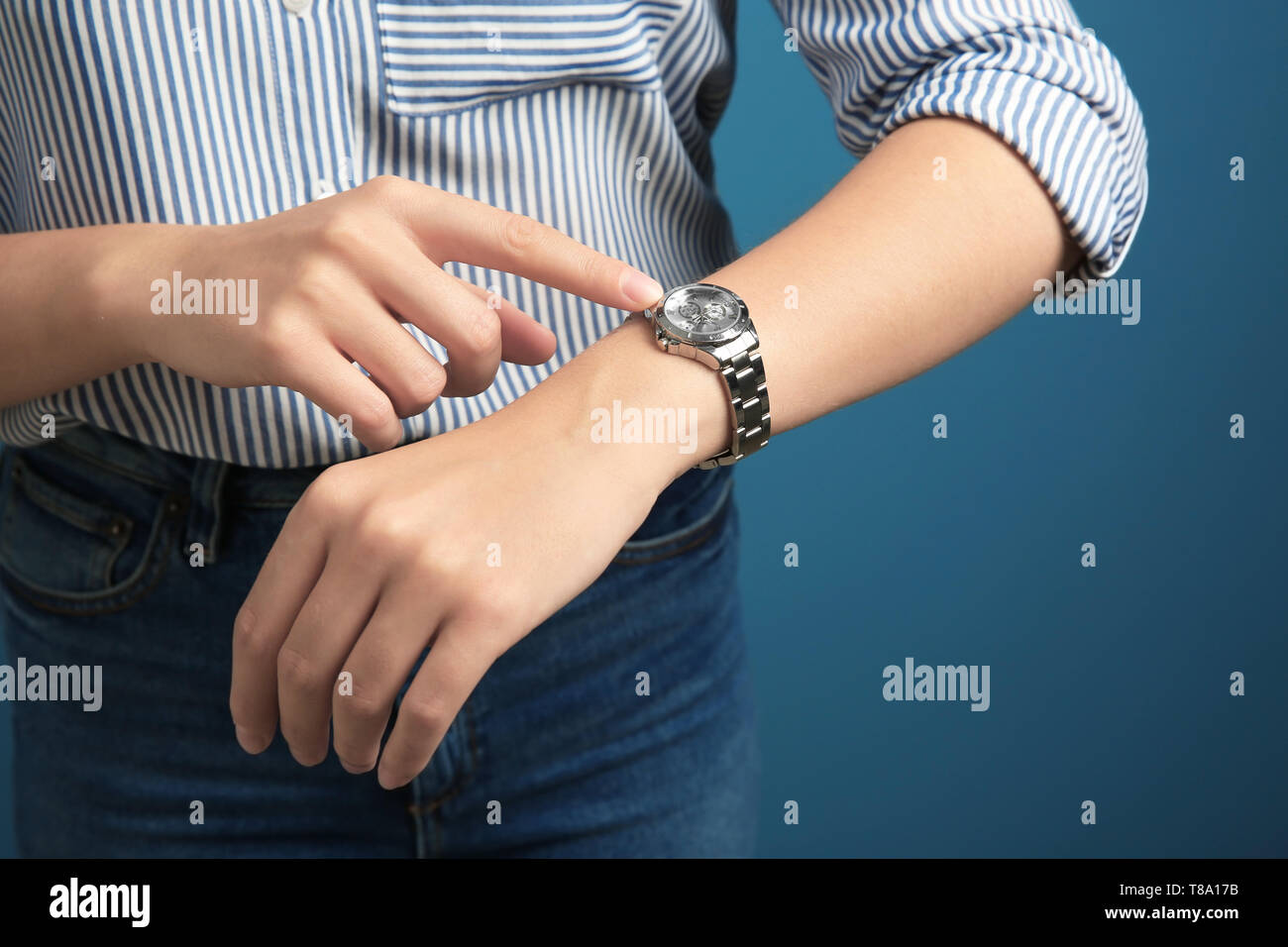 Woman looking at her watch on color background, closeup. Time ...