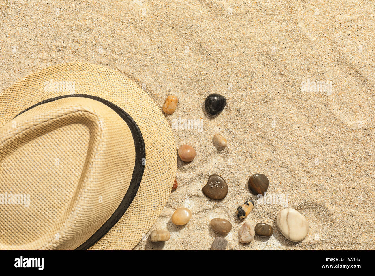 Hat and pebbles on beach sand Stock Photo - Alamy