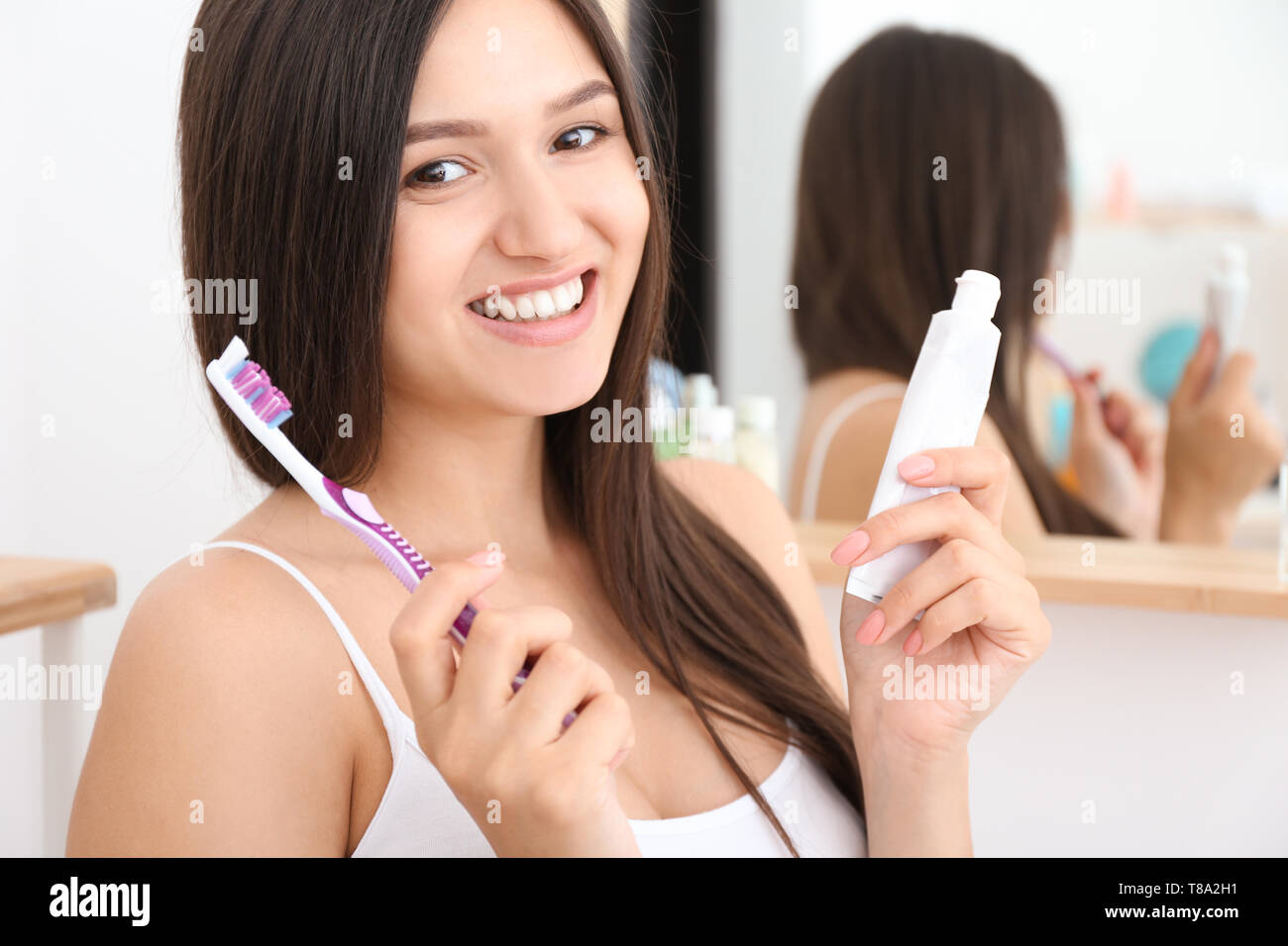 Young woman with toothpaste and brush in bathroom Stock Photo - Alamy