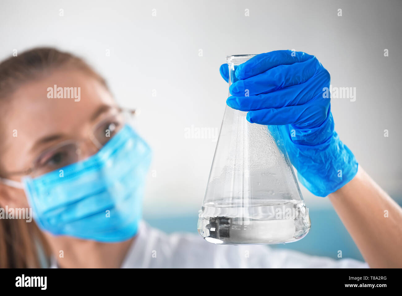 Scientist holding glass flask with sample in laboratory Stock Photo - Alamy