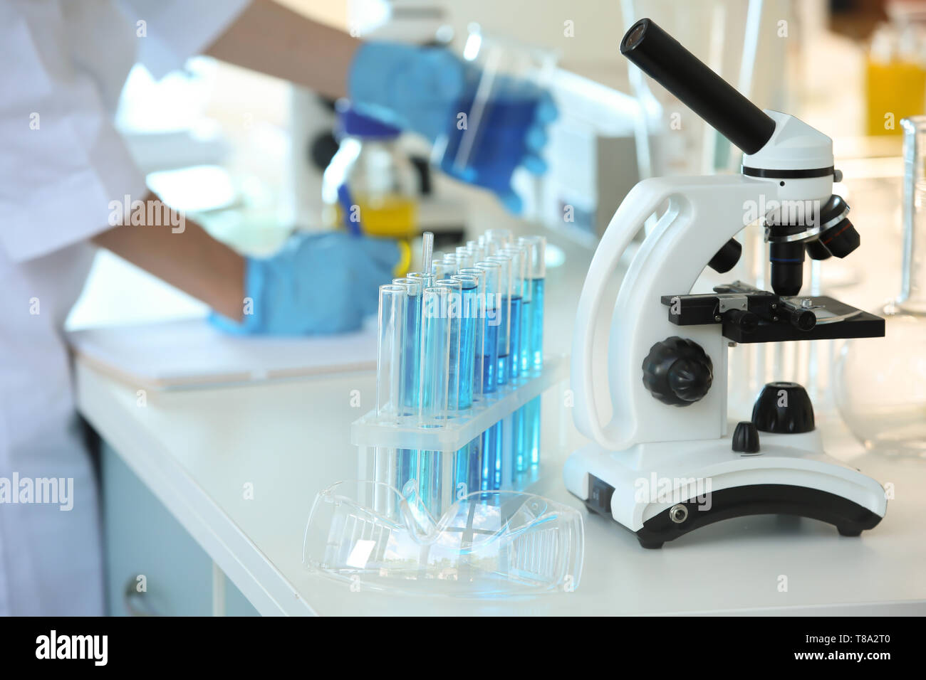 Test tubes with samples and modern microscope on table in laboratory ...
