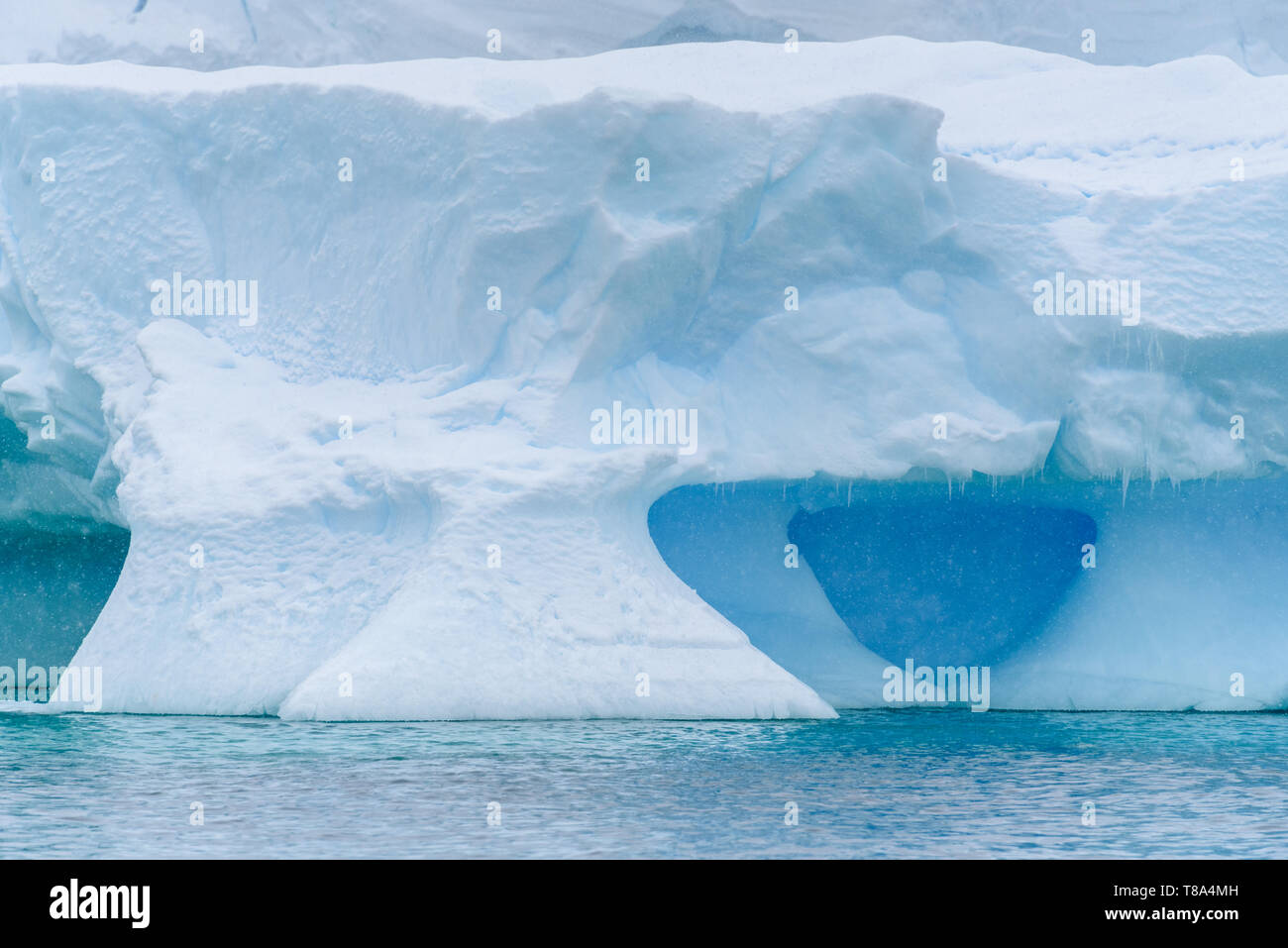 Sculptural iceberg shrouded in fog and floating in the waters of ...