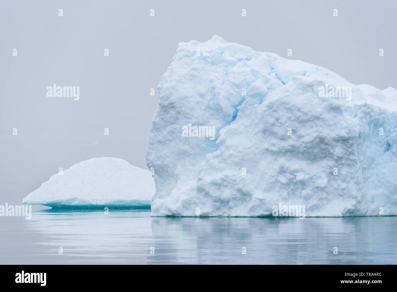 Sculptural iceberg shrouded in fog and floating in the waters of ...