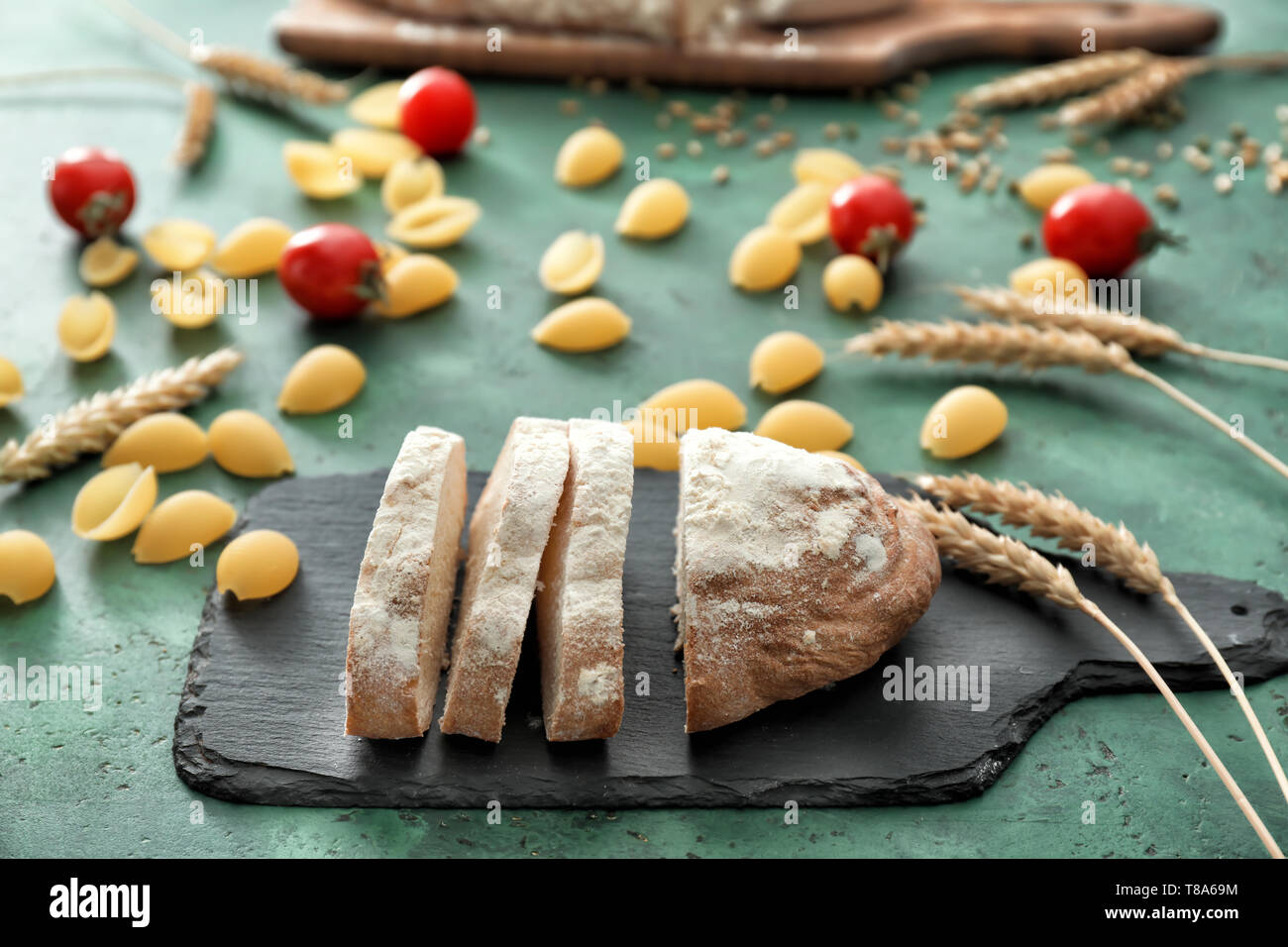 Sliced wheat bread with pasta and spikelets on color table Stock Photo ...
