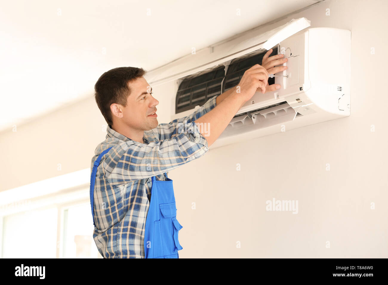 Electrician repairing air conditioner indoors Stock Photo - Alamy