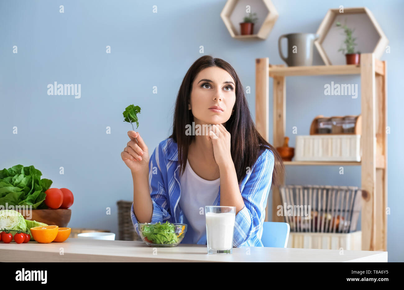 Reluctant woman eating healthy salad with vegetables indoors. Diet ...