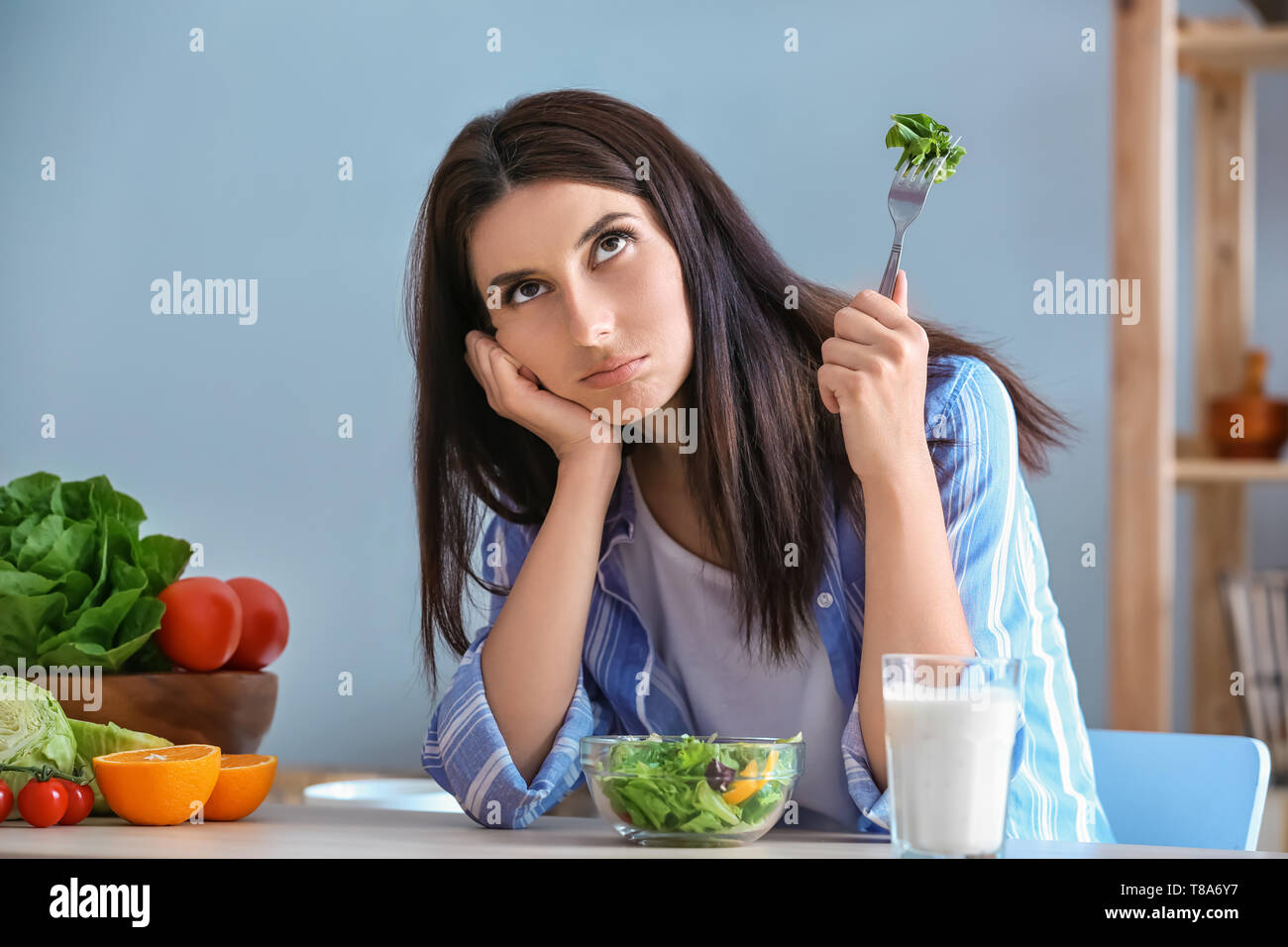 Reluctant woman eating healthy salad with vegetables indoors. Diet ...