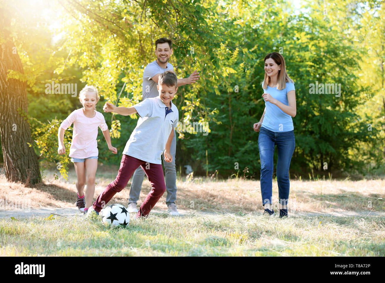 Happy family playing football outdoors Stock Photo - Alamy