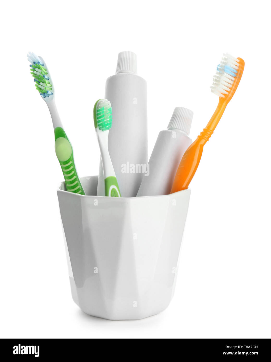 Cup with toothbrushes and paste on white background Stock Photo - Alamy
