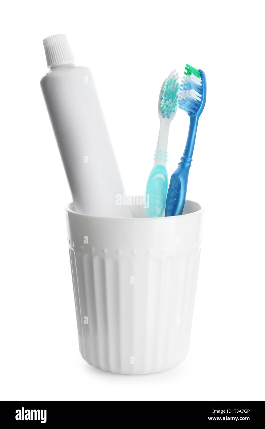 Cup with toothbrushes and paste on white background Stock Photo - Alamy