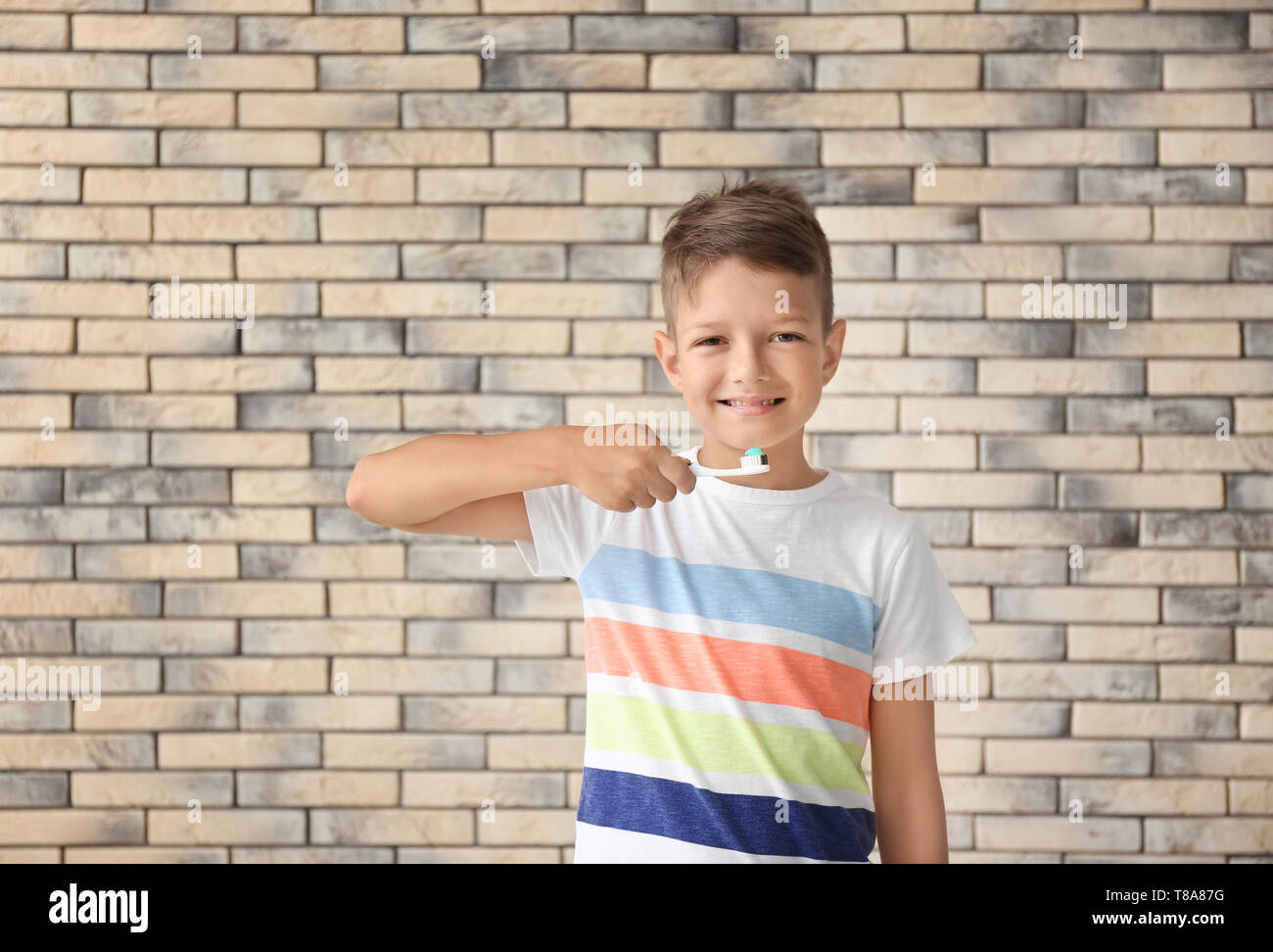 Little boy brushing teeth against brick wall Stock Photo - Alamy