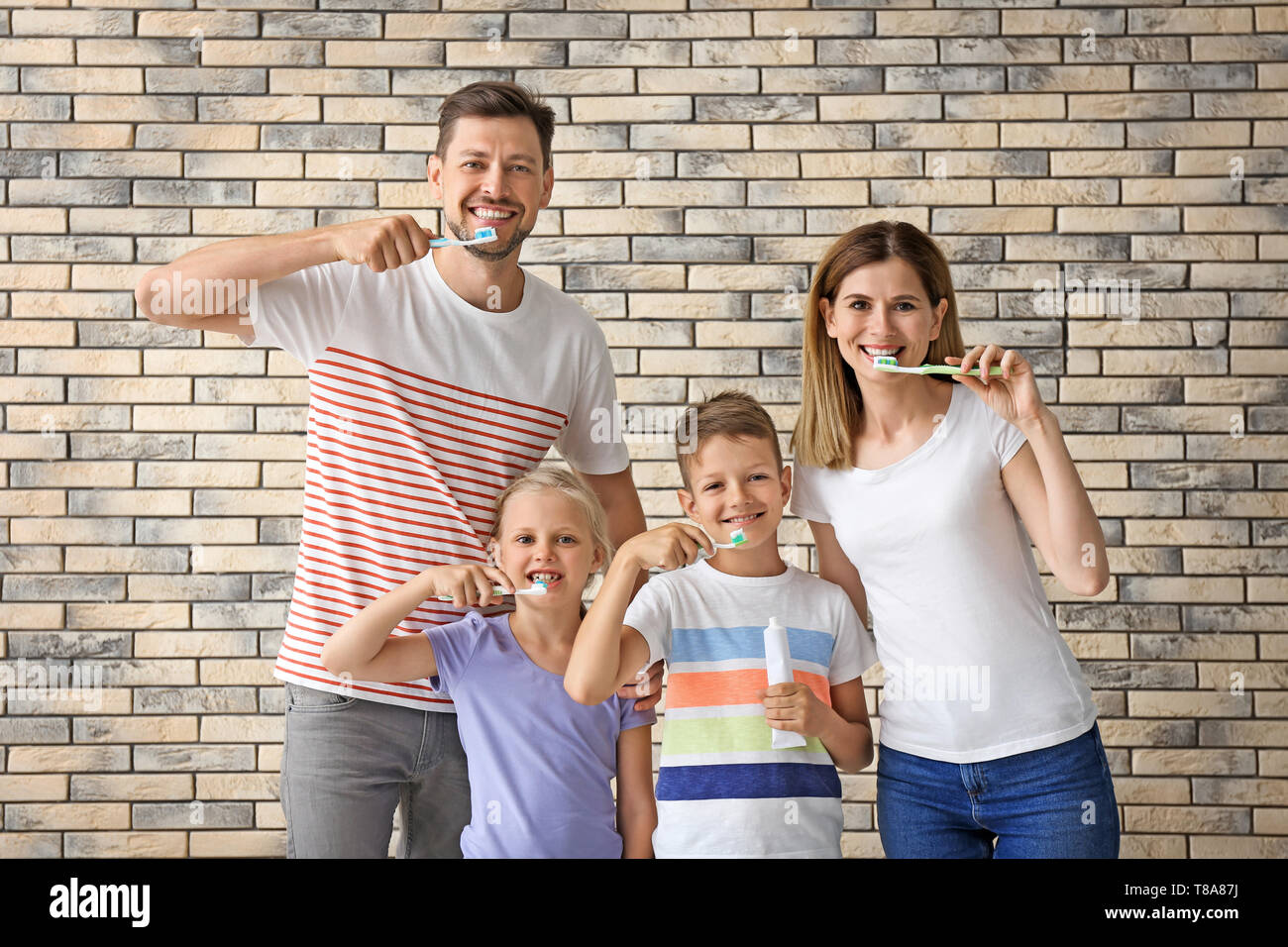 Family brushing teeth against brick wall Stock Photo - Alamy