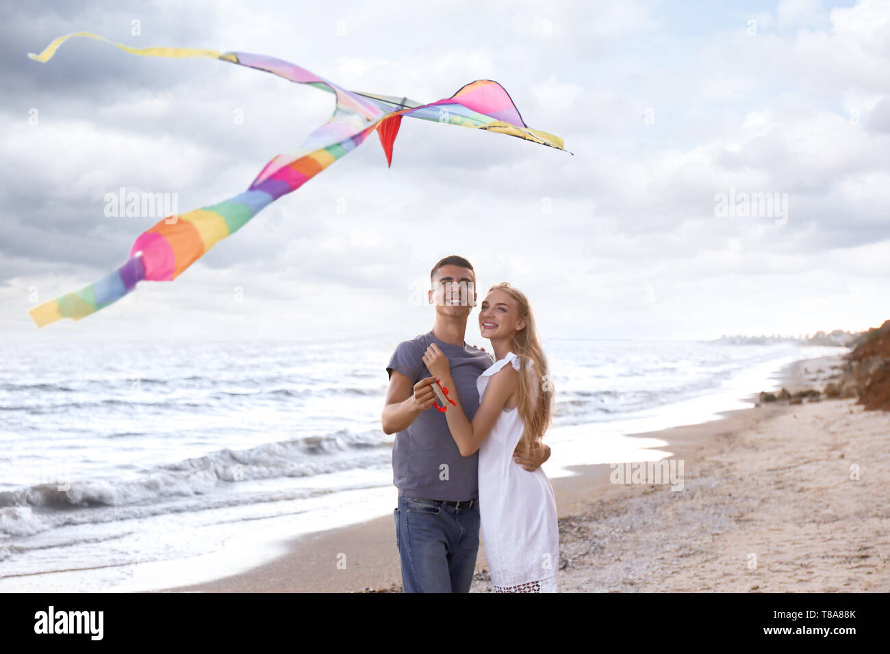 Happy young couple flying kite near sea Stock Photo - Alamy