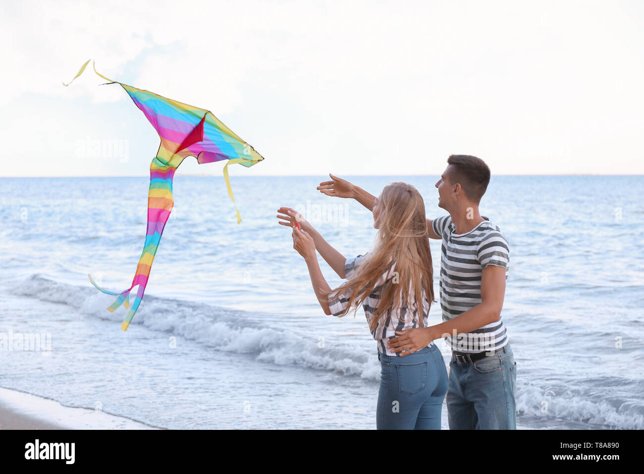 Happy young couple flying kite near sea Stock Photo - Alamy