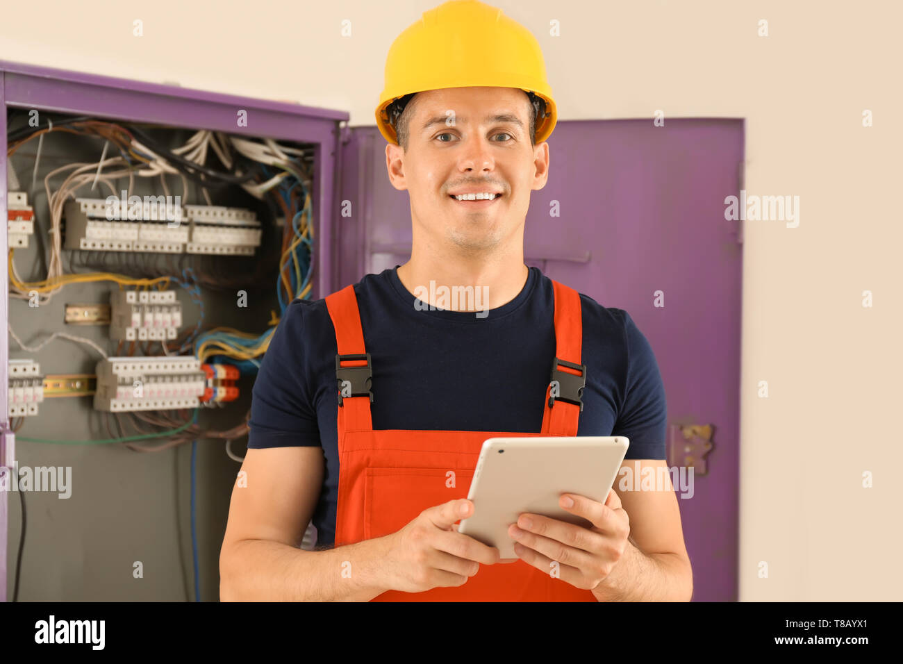 Electrician with tablet PC near distribution board indoors Stock Photo ...