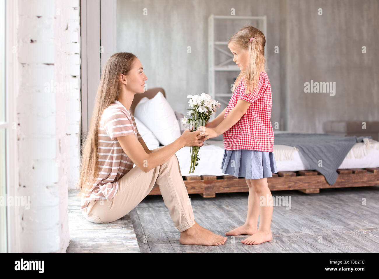 Cute little girl giving flowers to her mother at home Stock Photo - Alamy