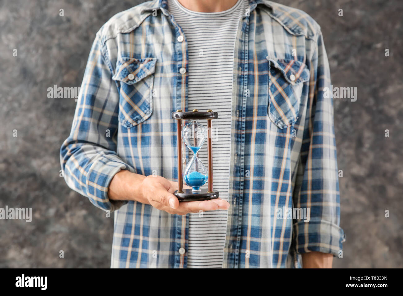 Man holding hourglass on grey background. Time management concept Stock ...