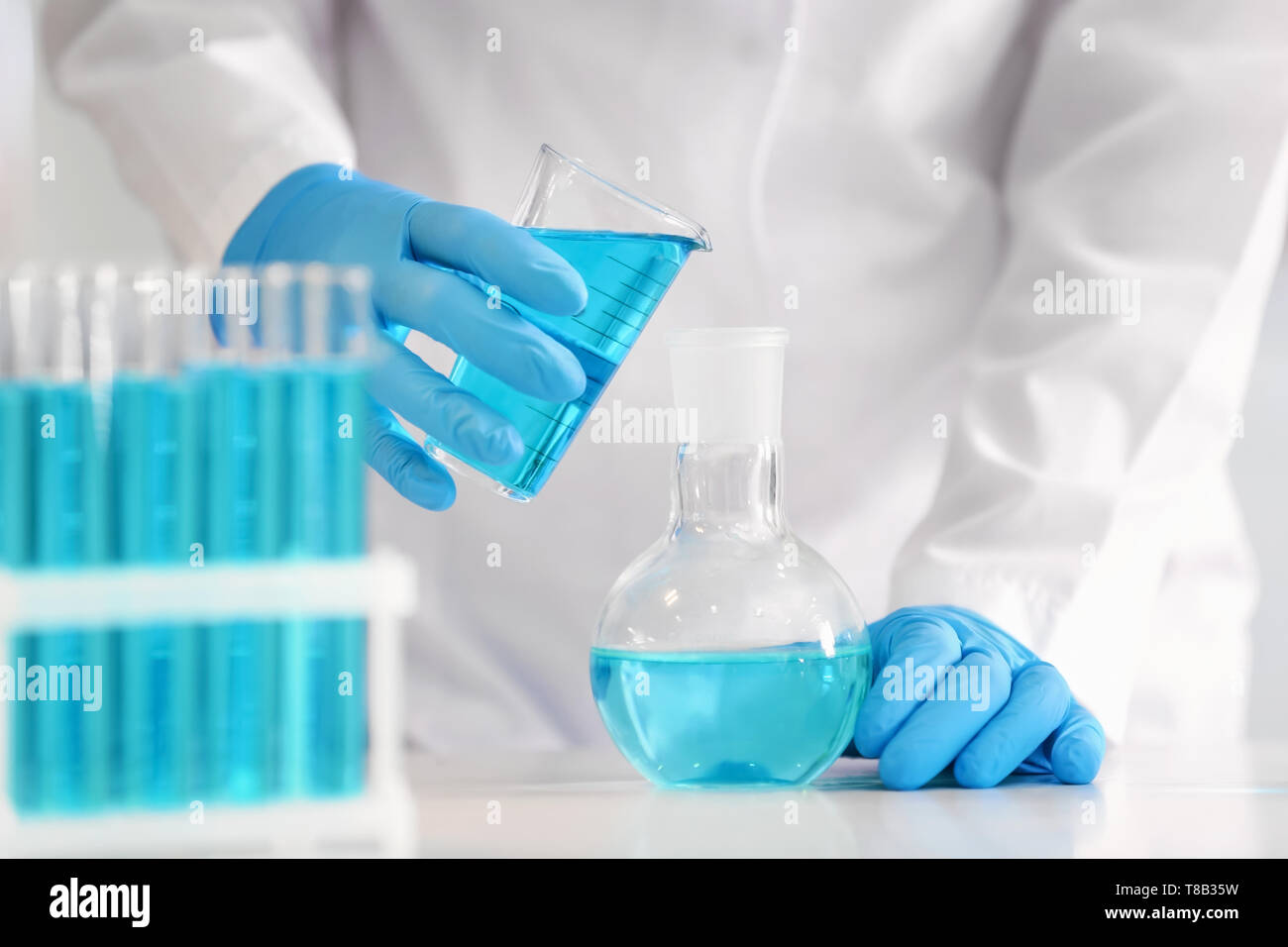 Scientist pouring color liquid into flask in laboratory Stock Photo - Alamy