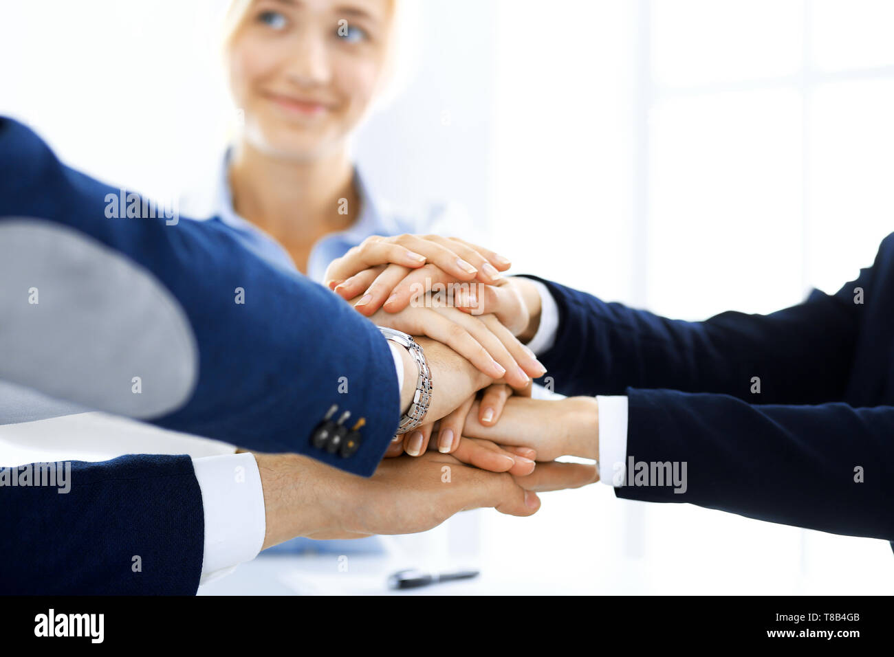 Business team showing unity with their hands together. Group of people joining hands and ...