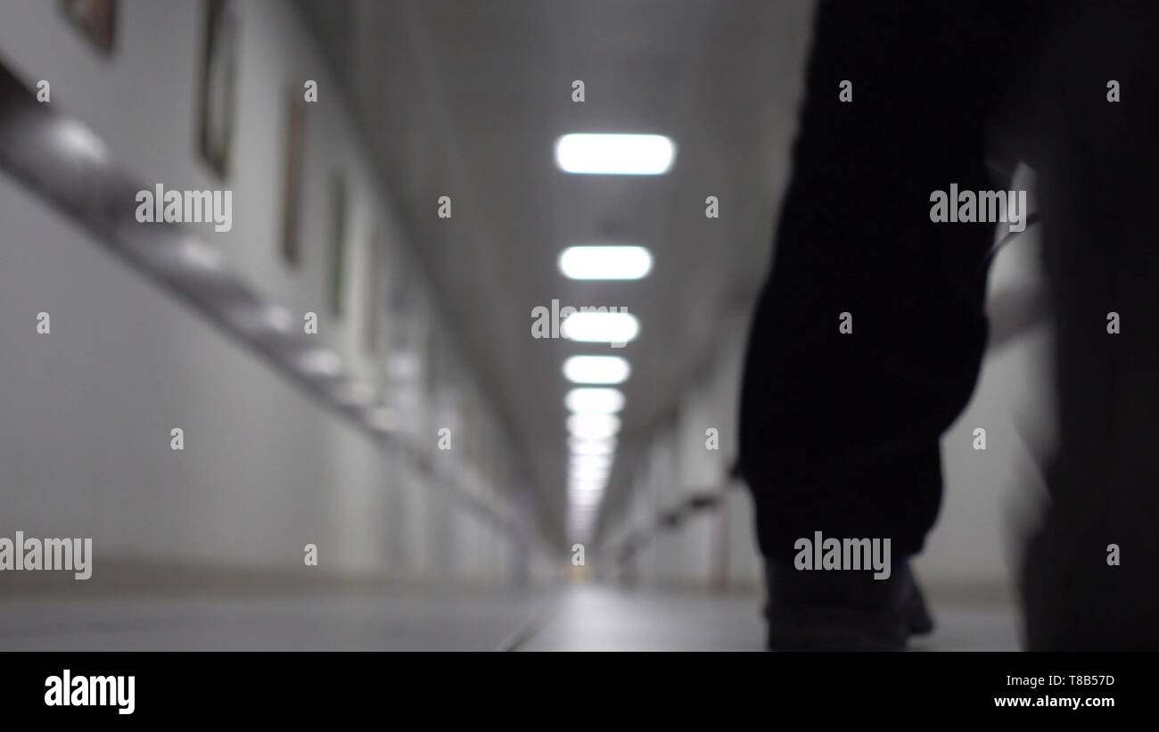 Man walks down the long white corridor. Blurred background. View from ...