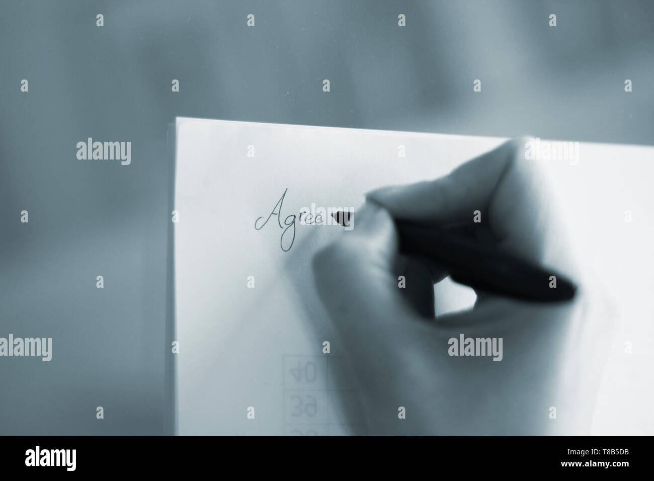 Young lady writing on paper with pencil in hand on table Stock Photo ...