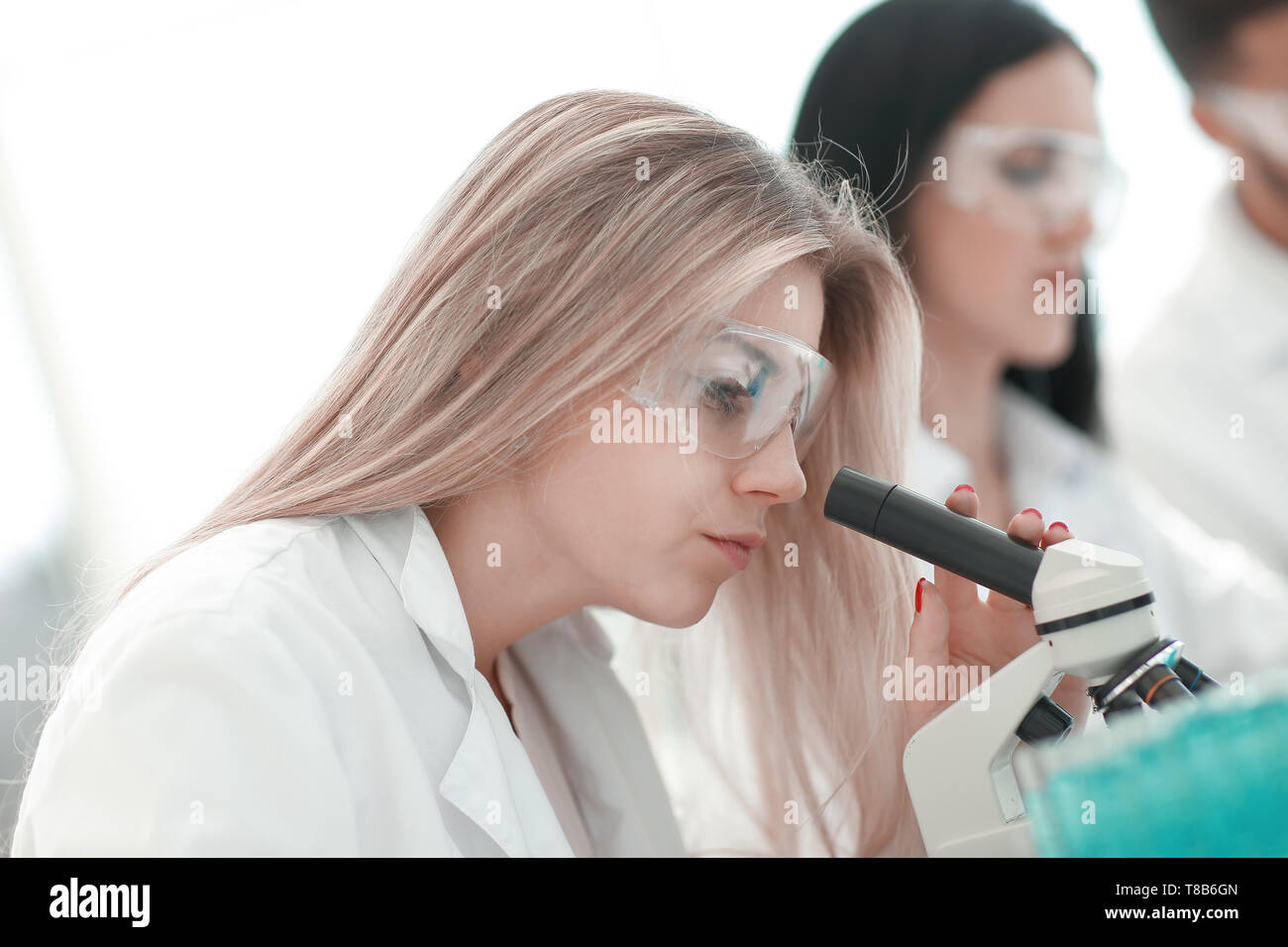 close up.serious female scientist looking into microscope in lab ...