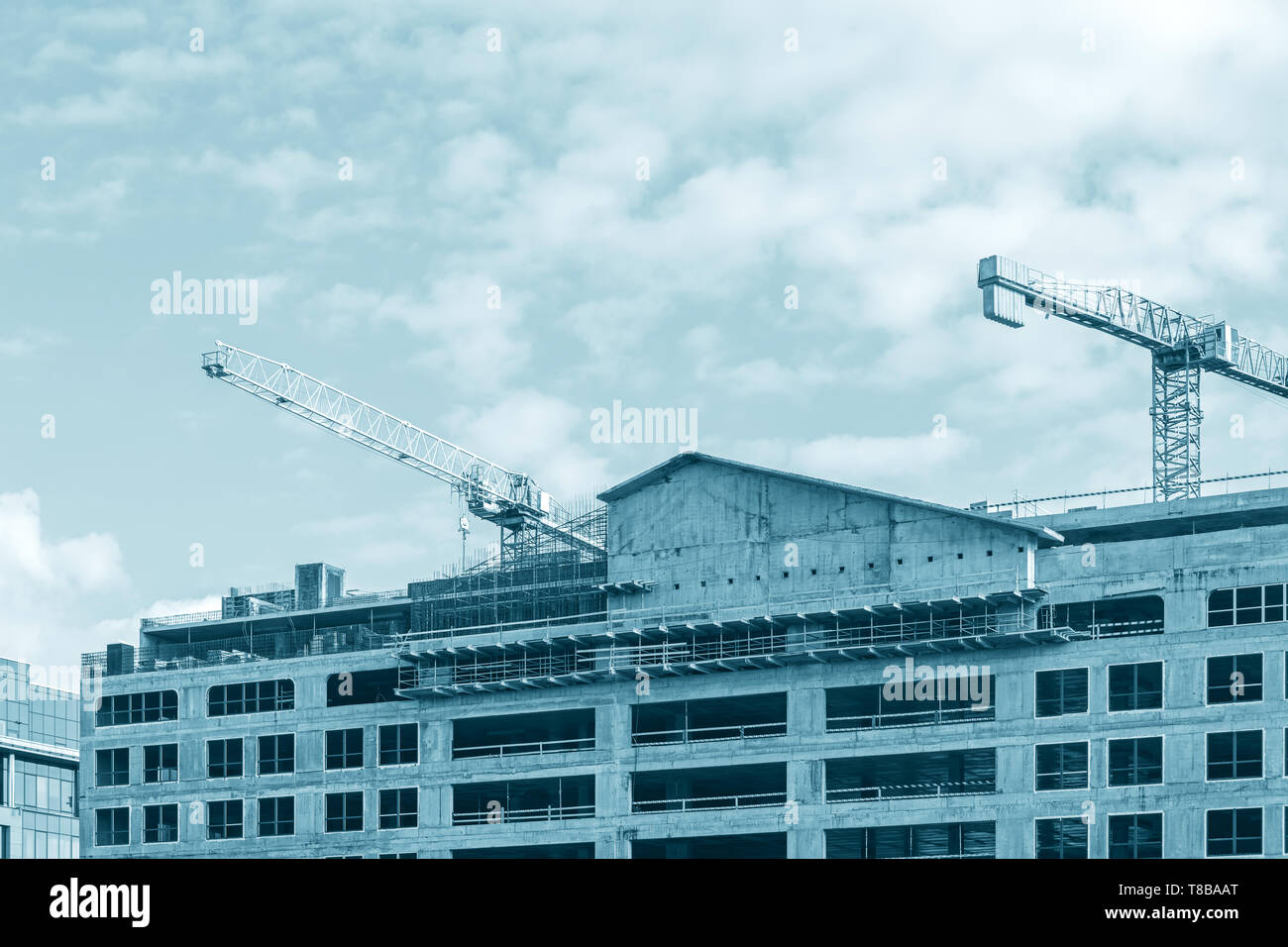 construction site with scaffolding building, high tower cranes against ...