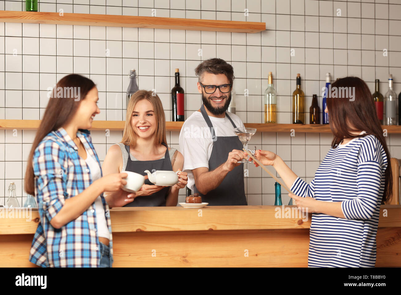 Female and male bartenders working with female clients in bar Stock ...