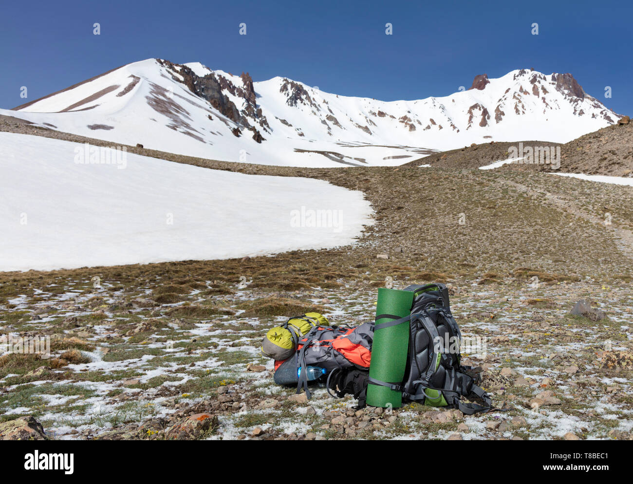 Backpacks of tourists are located at the foot of the mountain against a ...