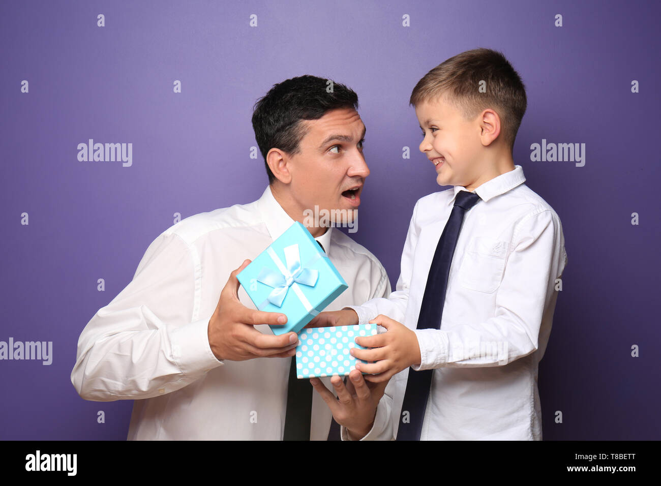 Little boy giving present to his father on color background Stock Photo ...