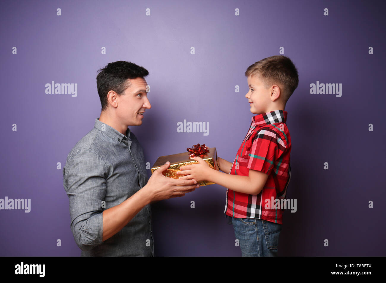 Little boy giving present to his father on color background Stock Photo ...