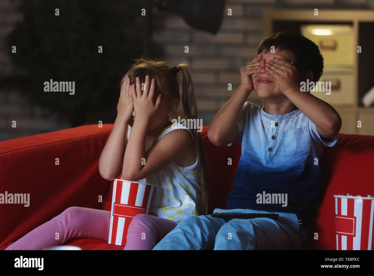 Cute children watching TV on sofa in evening Stock Photo - Alamy